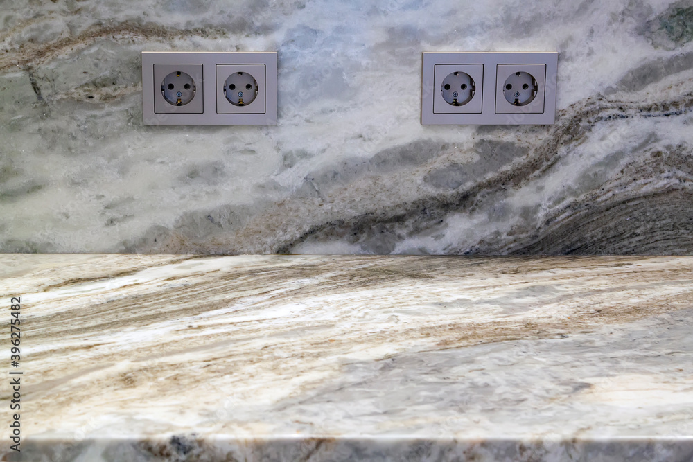 Beige marble table with electric outlets on stone wall texture ...