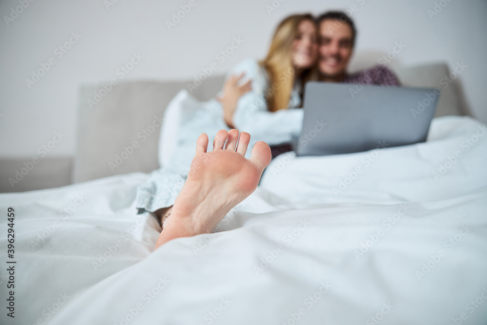 Barefoot young woman cuddling with boyfriend in bed Stock Photo | Adobe ...