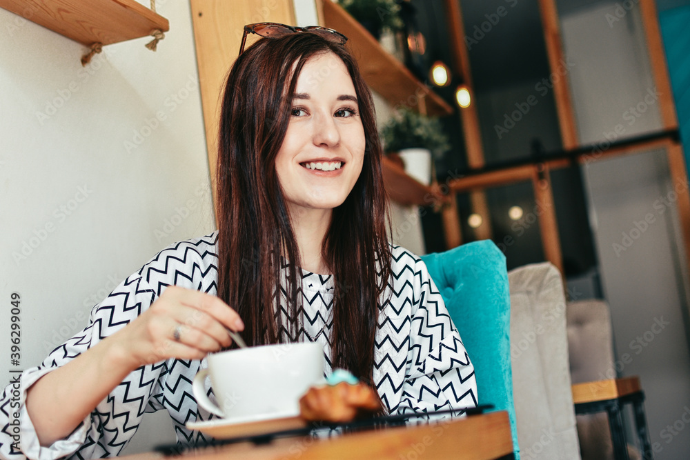 Beautiful European girl eats Eclair dessert and drinks cappuccino ...