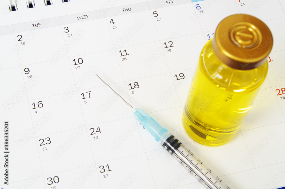 Vaccine and syringe on calendar background. Vaccination day, prevention ...