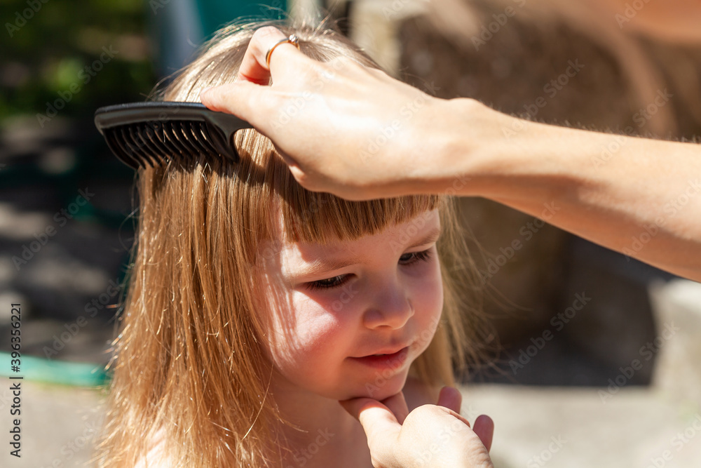 Foto de Mother combing her daughters hair, child being combed by her ...