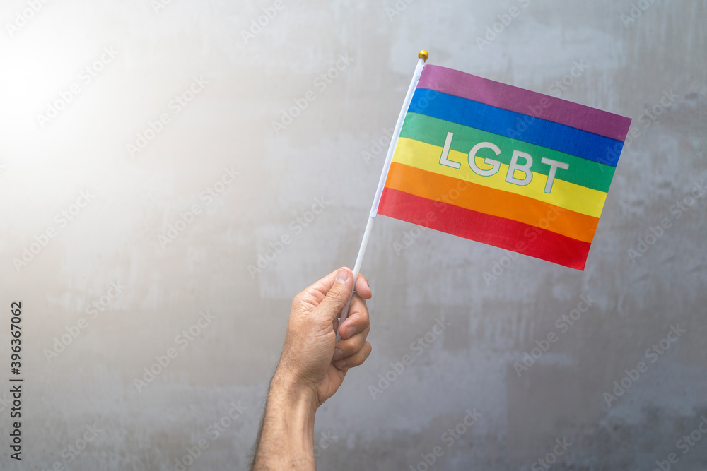 Person hand holding and waving an LGBT pride flag. Multicolored peace ...