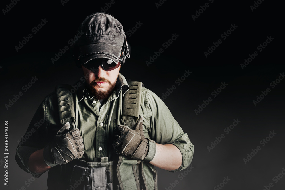 Soldier in armor vest and tactical protection outfit standing on black ...
