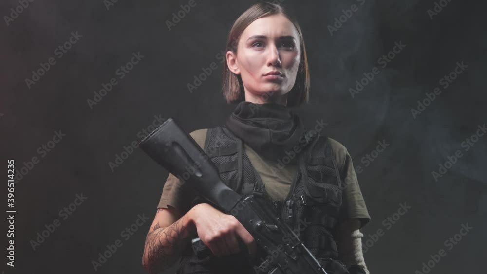 Tattooed and stylish female soldier with short haircut in dark military ...