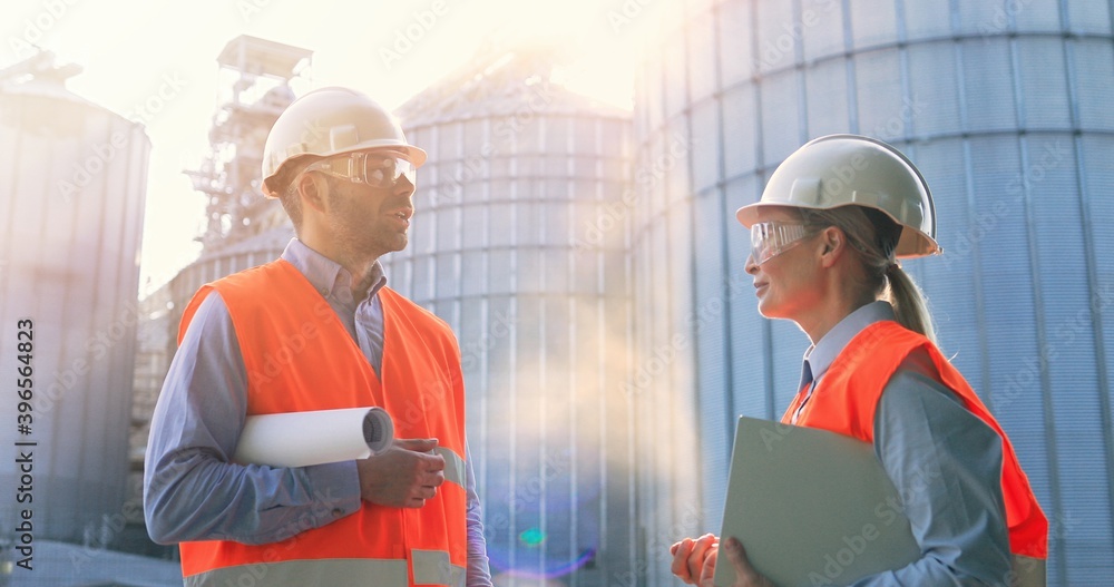 Side view of male and female Caucasian engineers in helmets talking ...