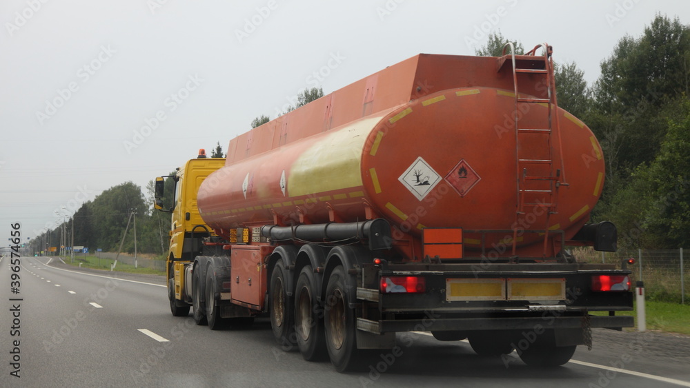 Modern orange semi truck fuel tanker with empty dangerous class sign on ...