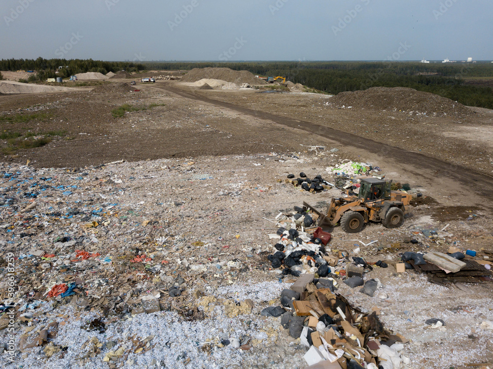 Aerial view of yellow buldozer on dumping site with different types of ...