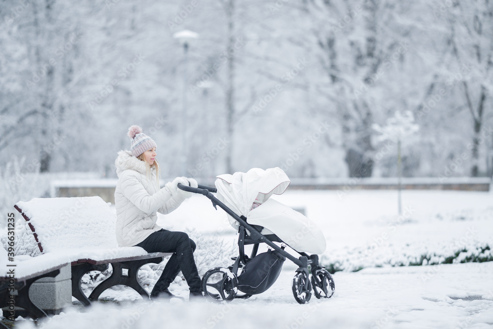 One young adult woman sitting on bench at town snowy park in white ...