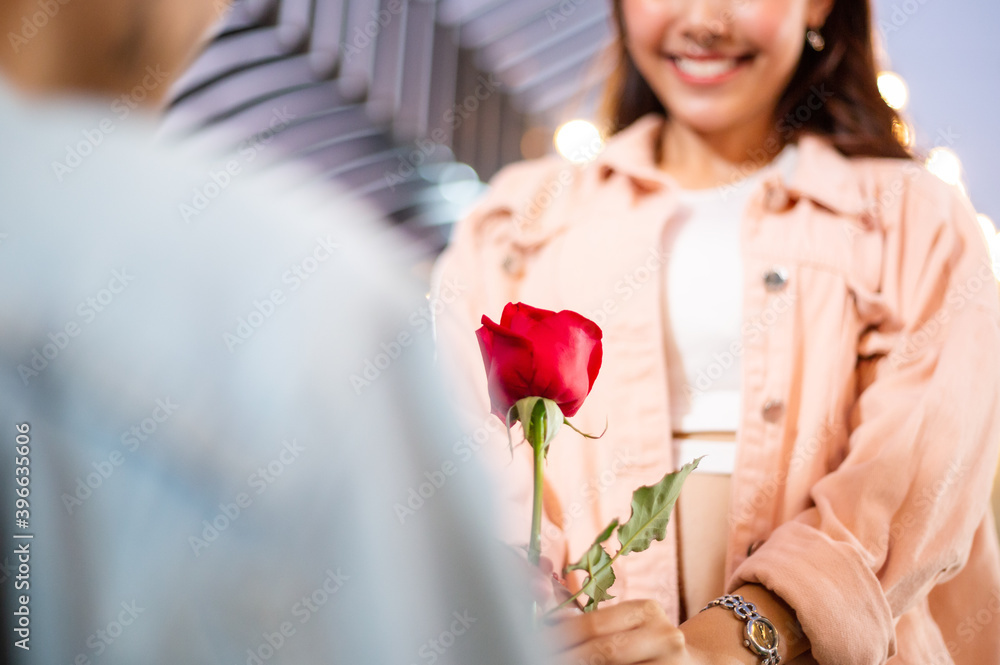 Smiling attractive Asian woman looks happy and surprise receiving rose ...