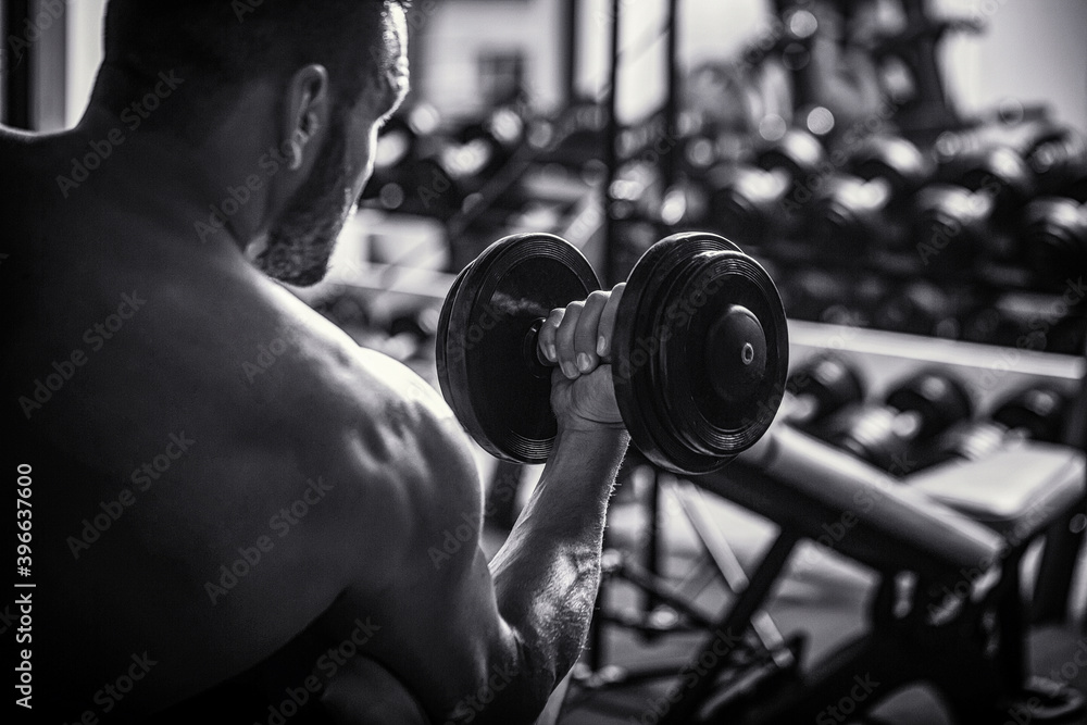 Bodybuilder working out with dumbbell weights at the gym. Man ...