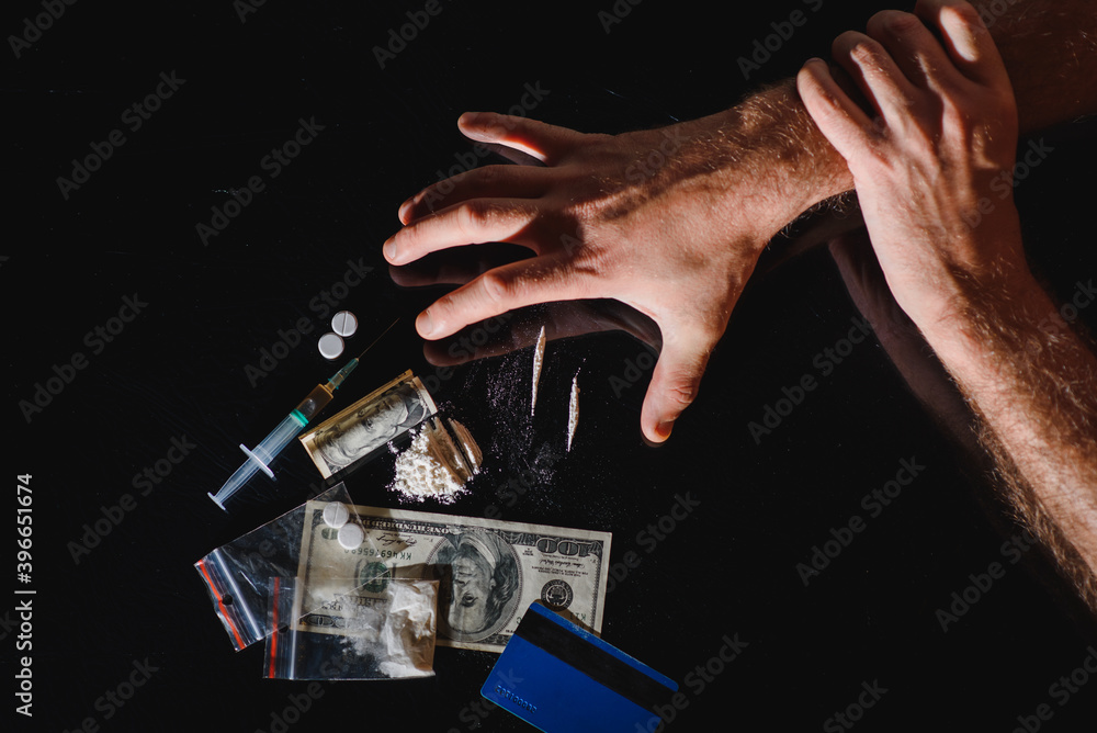 Man's hands trying to abstain from drugs on dark table with cooked ...