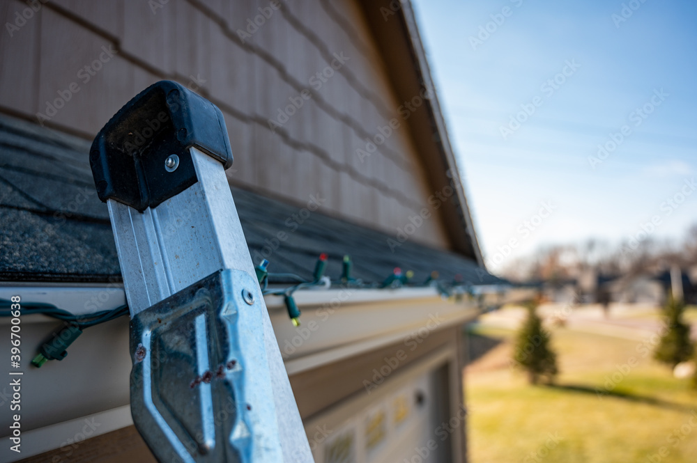extension step ladder against side of roof with a strand of Christmas ...