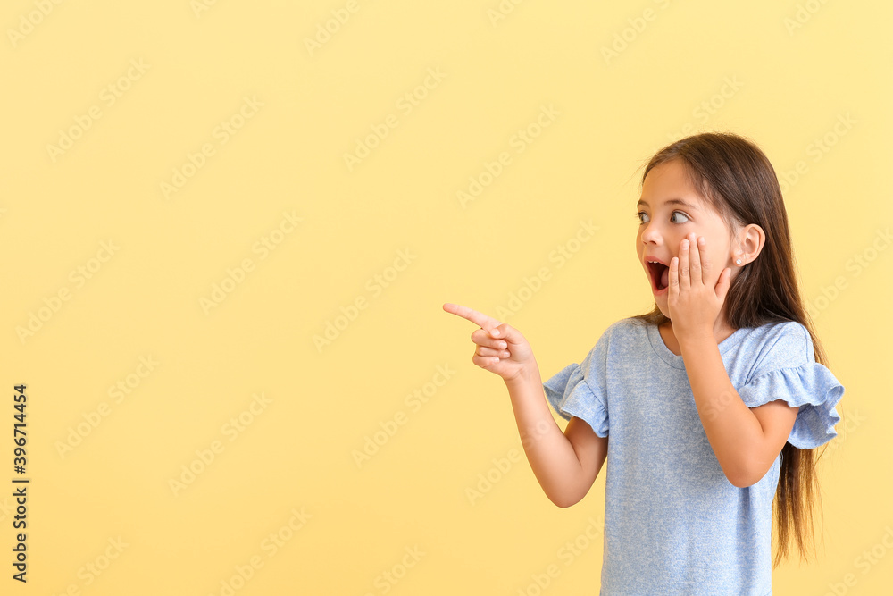 Surprised little girl pointing on something on color background Stock ...