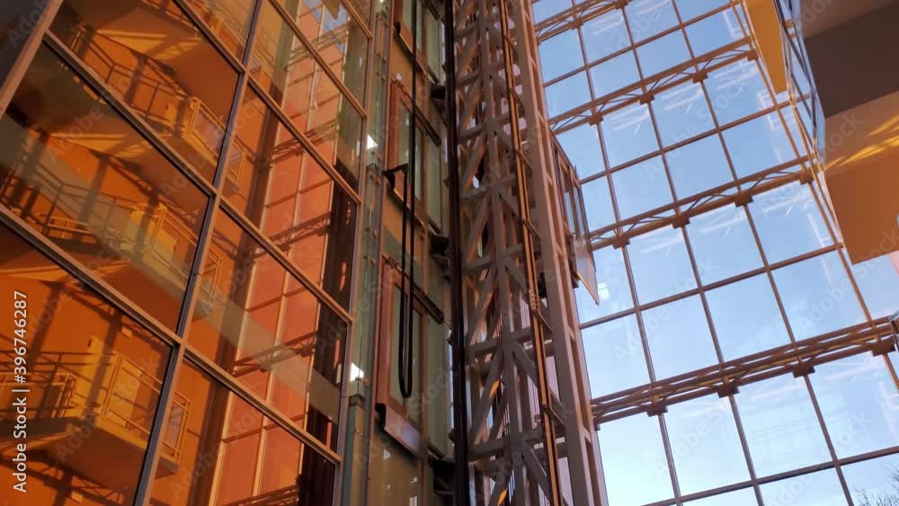 Skyscraper walls in golden hour sunlight. Modern elevator moves down ...