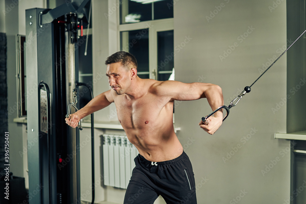 Bodybuilder doing butterfly on cable pull for better definition of his ...