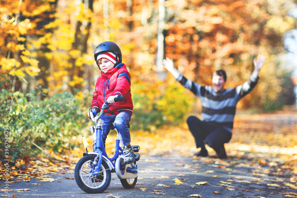 Little kid boy learning moving on bicycle. His father teaching his son ...