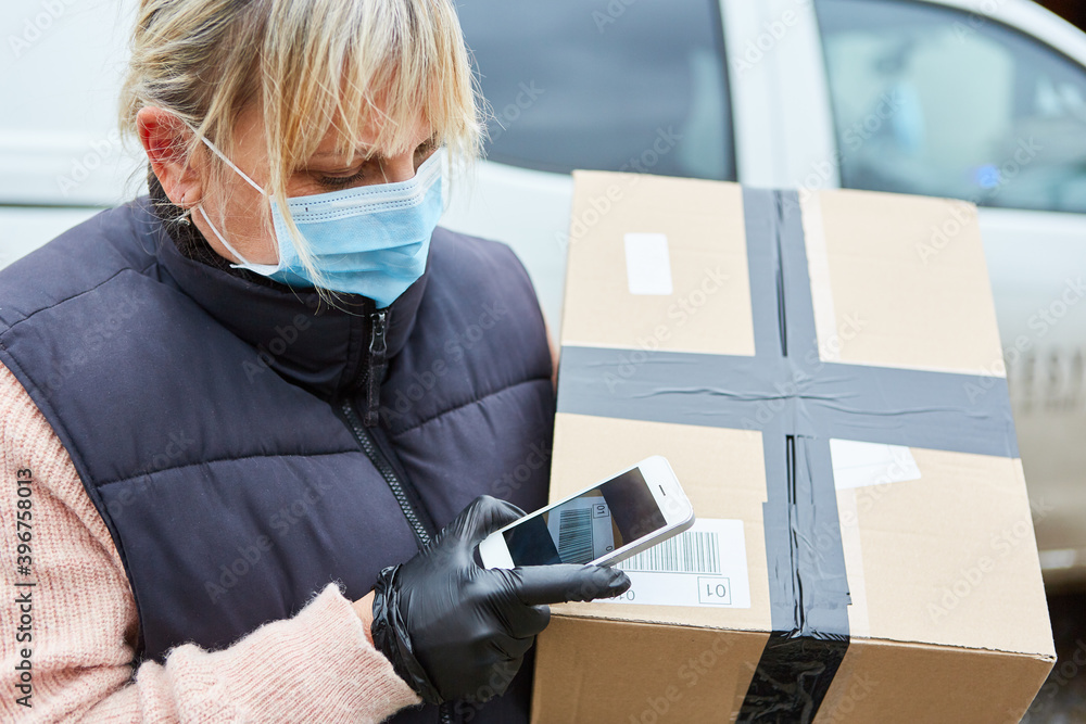 Parcel messenger with face mask confirms delivery with smartphone Stock ...