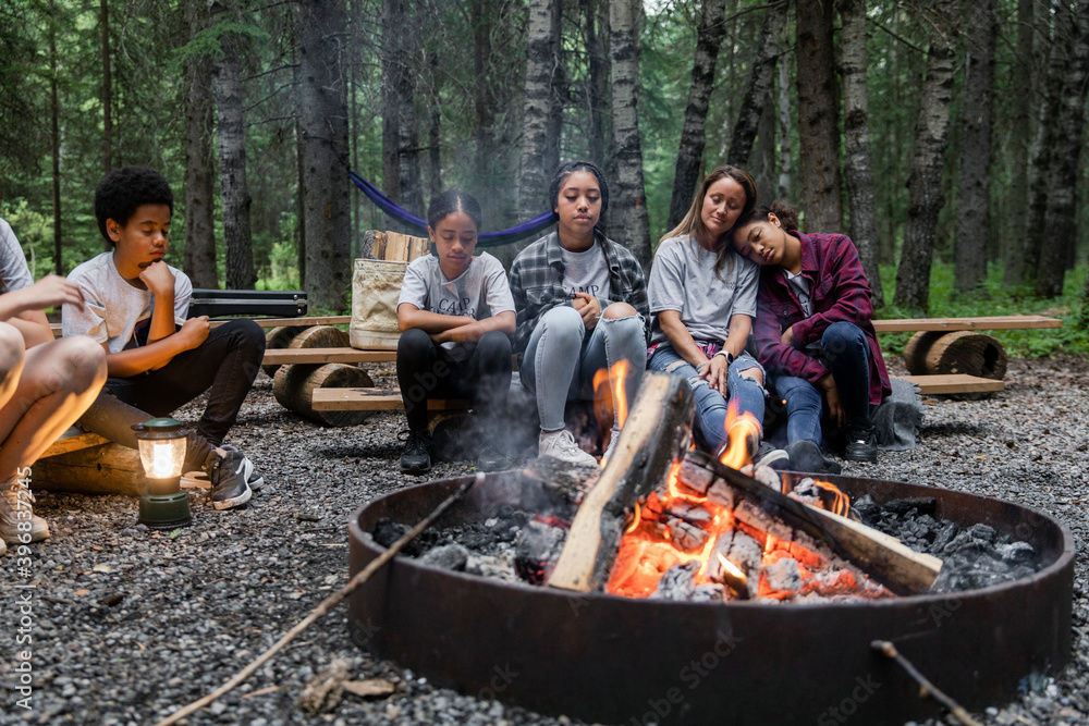 Family sitting around campfire in forest Stock Photo | Adobe Stock