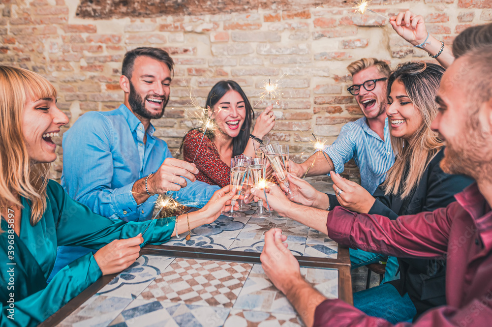 Young people toasting with champagne flutes and sparkling bengal lights ...