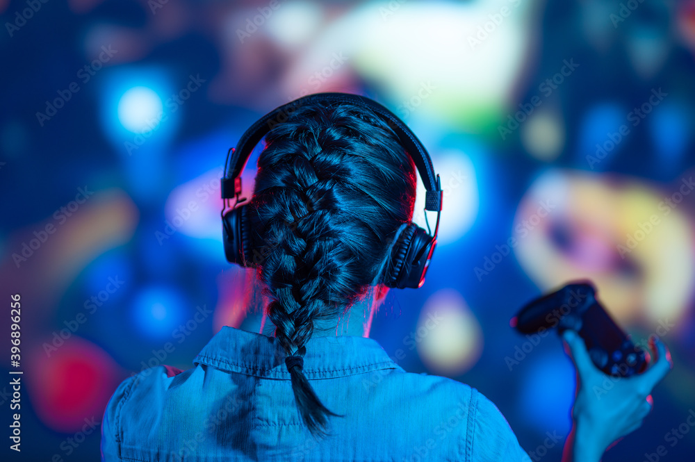 View from back of gamer woman with pigtail playing video game at home ...