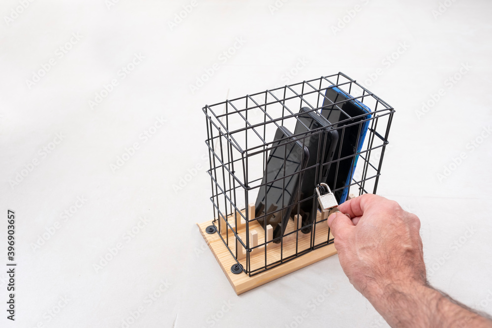 hand opening or closing the lock on a cage with three mobile phones ...