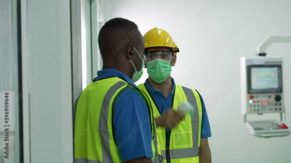 Multi ethnic group of production line workers check body temperature ...