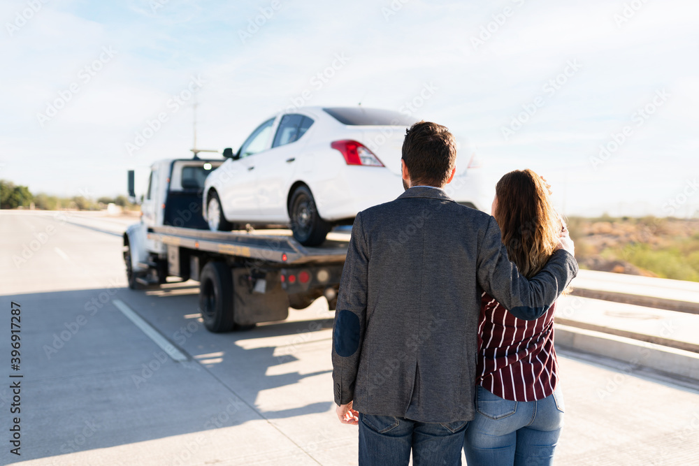 Man and young women hugging as they see their car being towed foto de ...