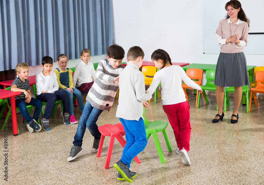 Group of cheerful school kids playing active games with teacher in ...