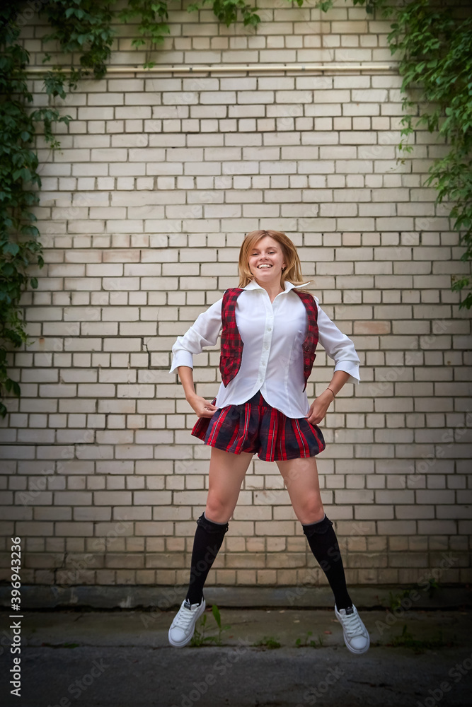 Young girl with short hair in a school checkered uniform outdoors ...