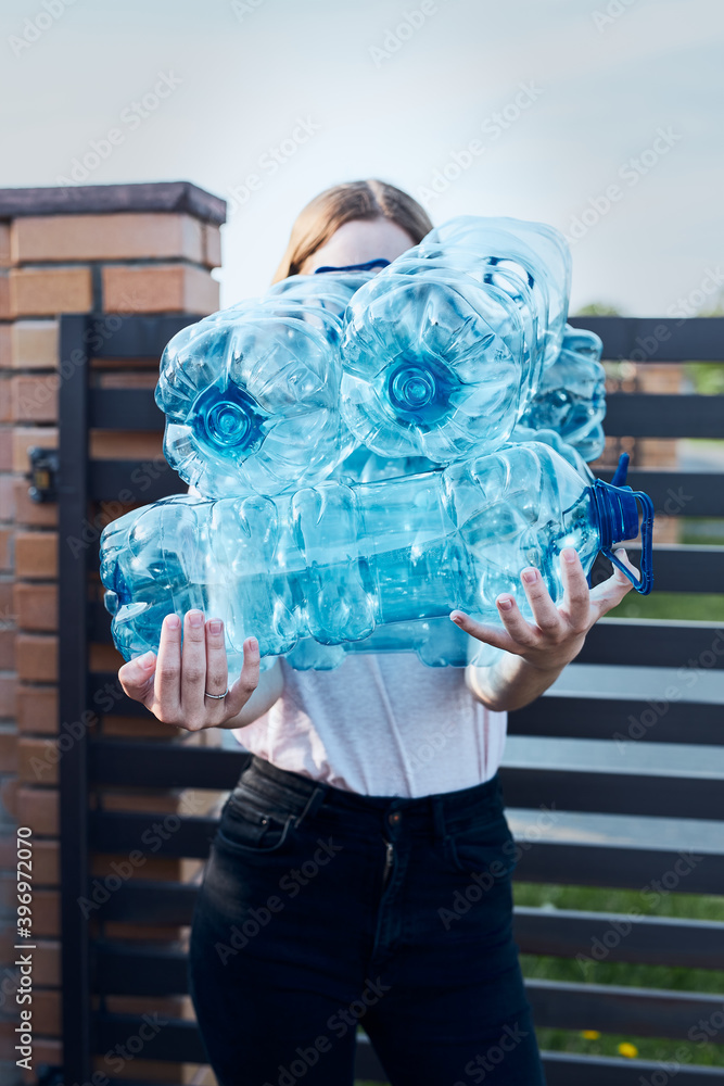 Young woman throwing out empty used plastic water bottles into trash ...