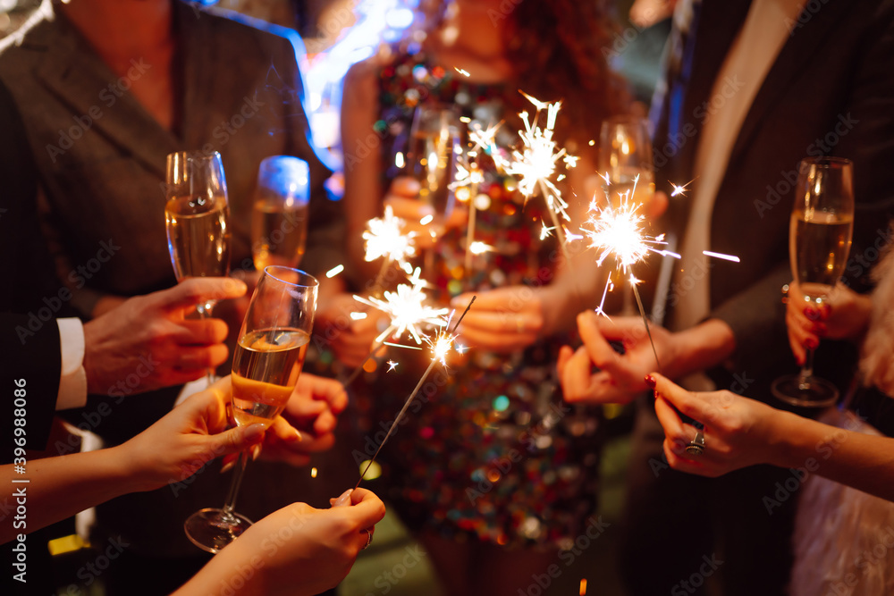 Foto de Glowing sparkles in hands. Group of happy people enjoying party ...