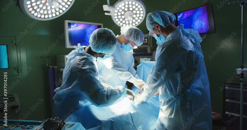 Mixed-races team of professional doctors surgeons in uniform performing ...