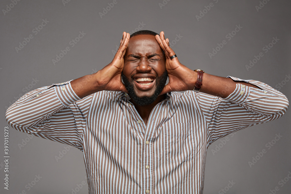 Excited African American man with short beard is grabbing his head and ...