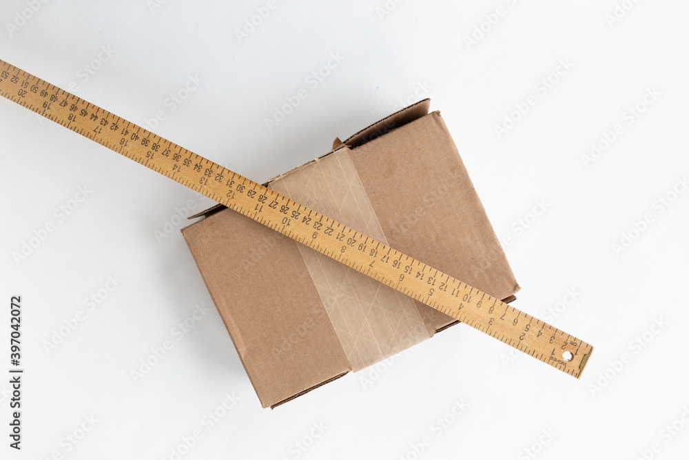 Cardboard shipping box placed on white background. Leaning on it is a ...