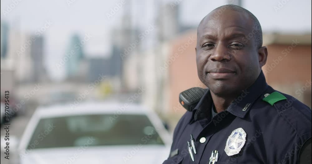 Police officer standing at police car and smiling Stock Video | Adobe Stock
