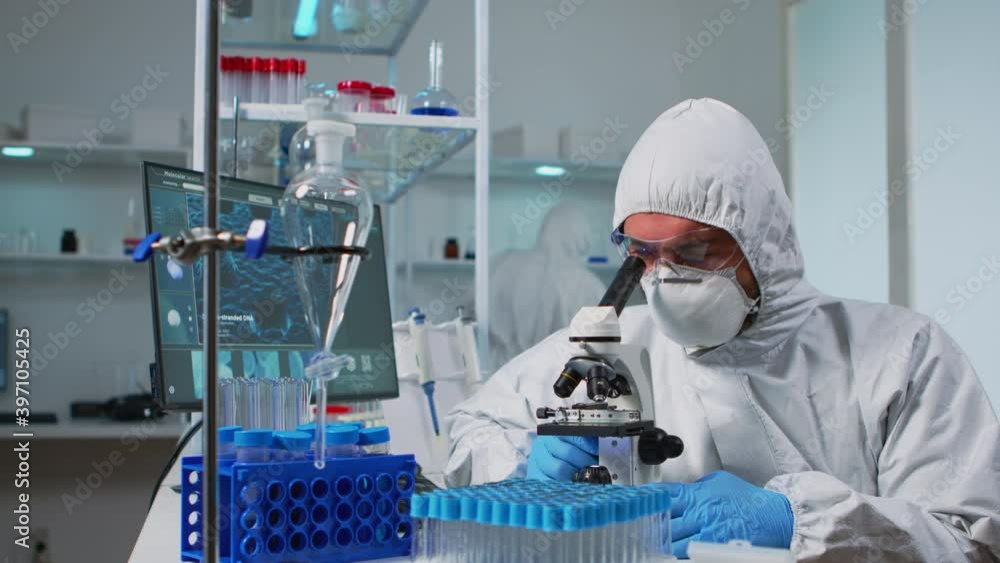 Biologist doctor in coverall checking DNA sample typing on pc in modern ...