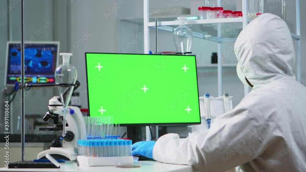 Doctor with coverall working at computer with green screen in modern ...
