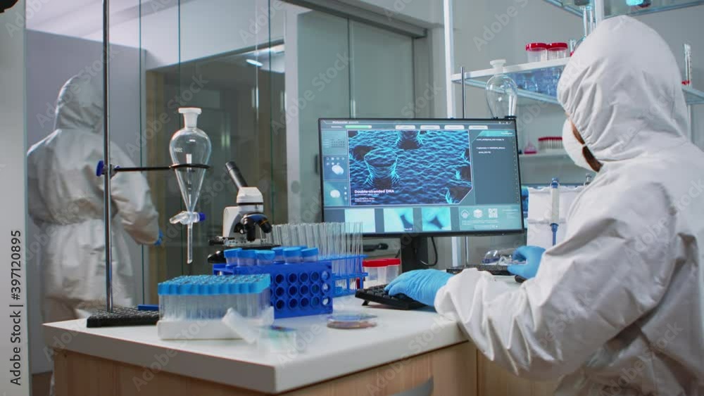 Chemist man in coverall typing on computer analysing vaccine evolution ...