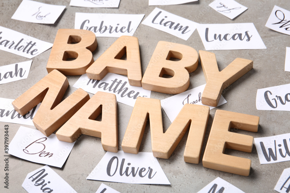 Paper sheets with different baby names, and wooden letters on grey ...