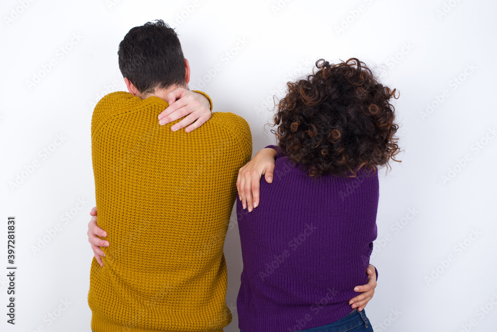 Young couple wearing knitted sweater standing against white wall ...