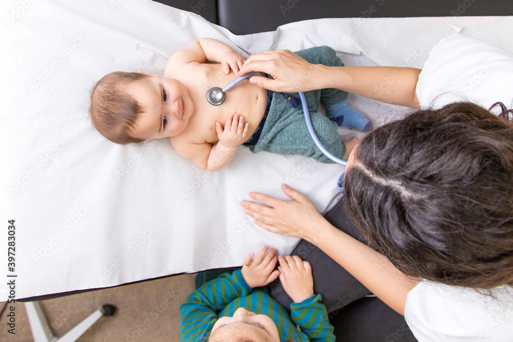 Little beautiful baby having a medical examination by a woman ...