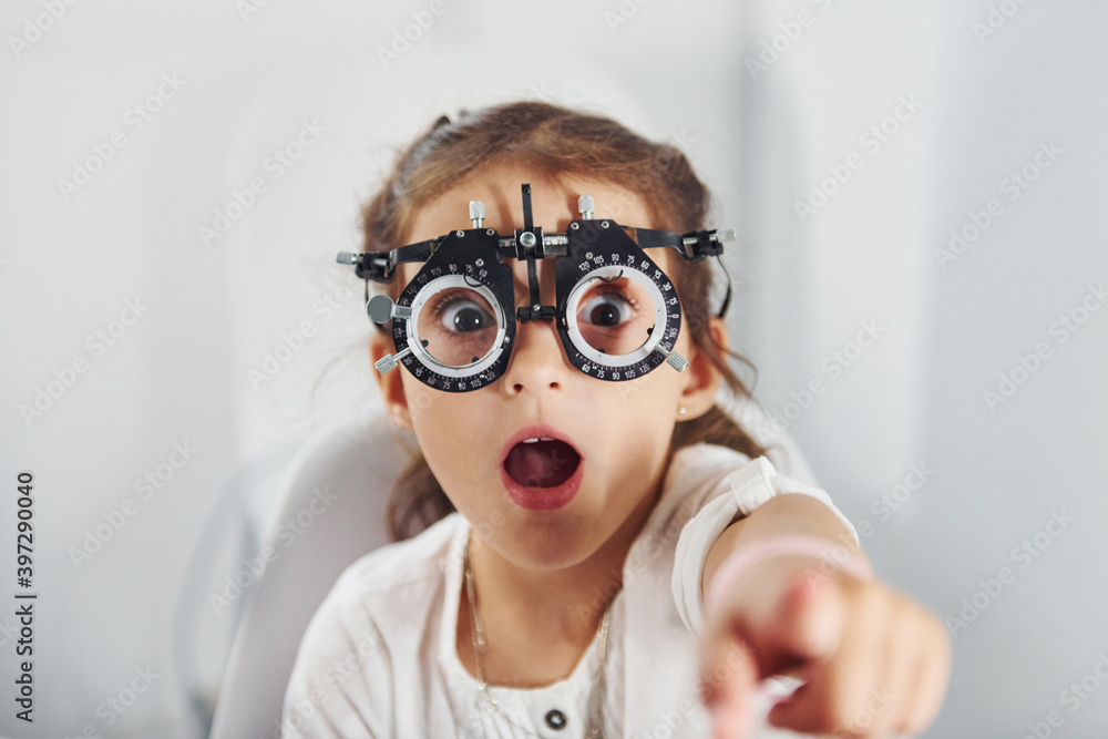 Cute little girl is in ophthalmology clinic with special tool on eyes ...