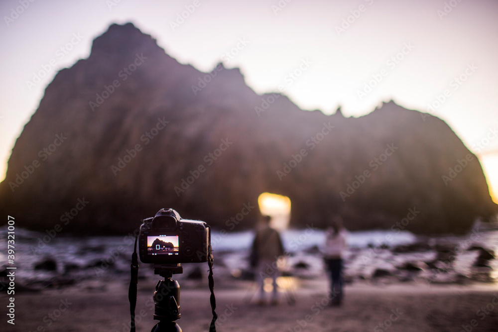 Camera on self-timer taking photograph of couple on beach, Big Sur ...