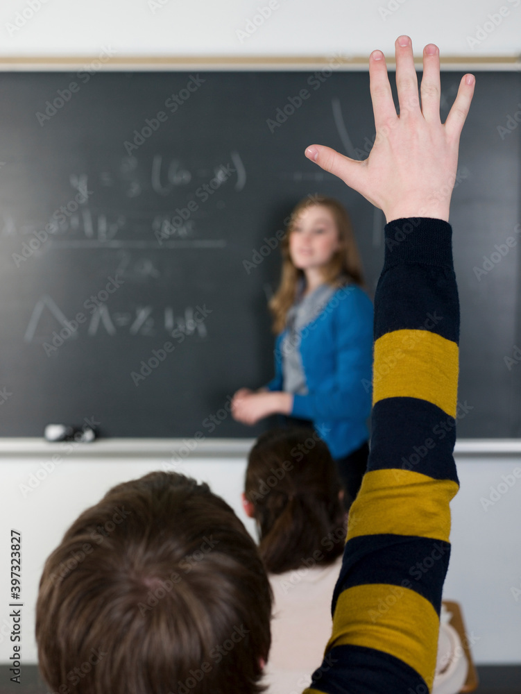 Student raising hand in classroom Stock Photo | Adobe Stock