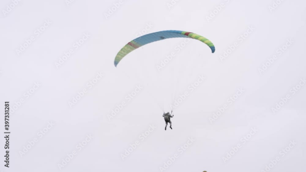 Rear view of a parachutist circling in the air with a wing parachute ...