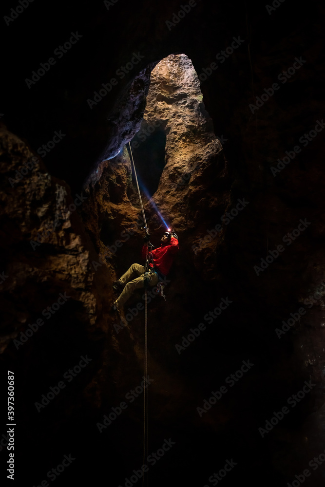 Rescuers or climber descends in a cave fast rope in the dark caves ...