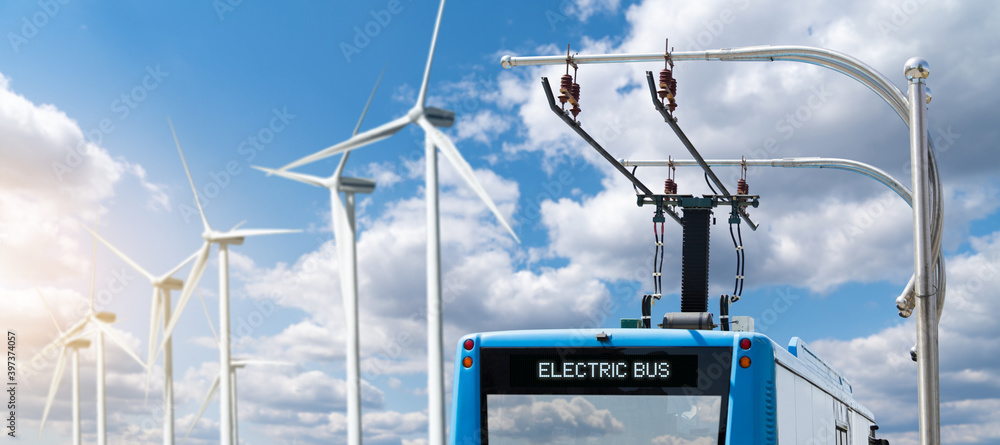 Electric bus at a stop is charged by pantograph on the background of ...