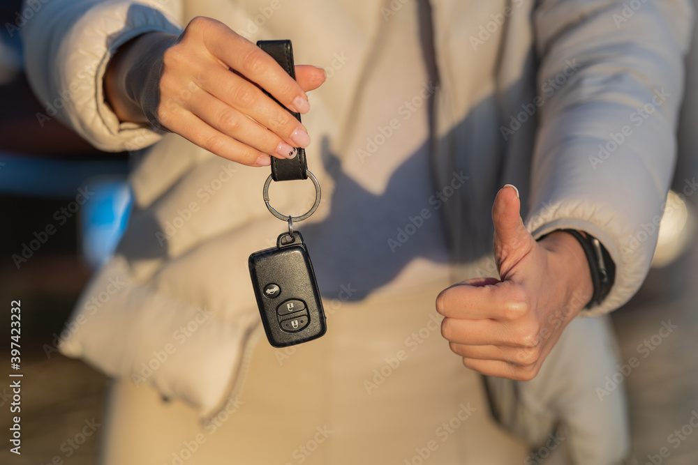 Foto de Woman holding key of her new car. Woman has got driving license ...