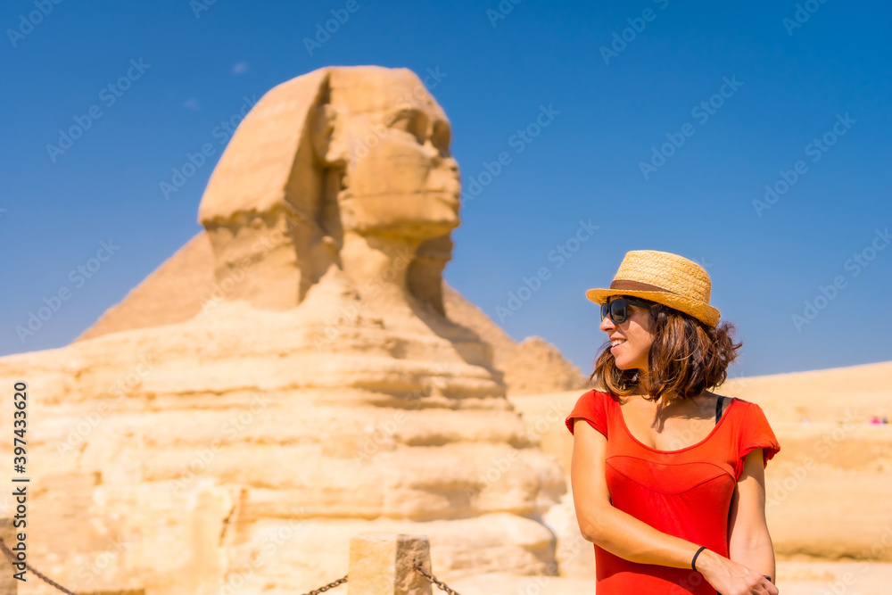 Portrait of a young tourist at the Great Sphinx of Giza dressed in red ...