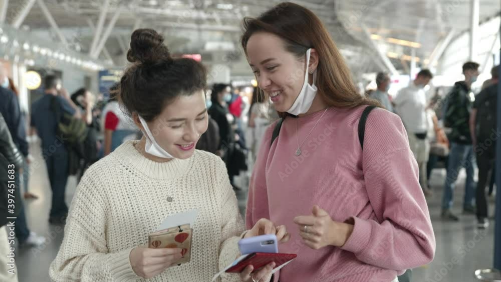 Two close friends women in medical mask on their chin in airport ...